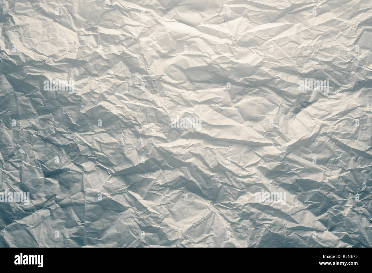 Wrinkled white paper sheet background under dramatic dark moody ...