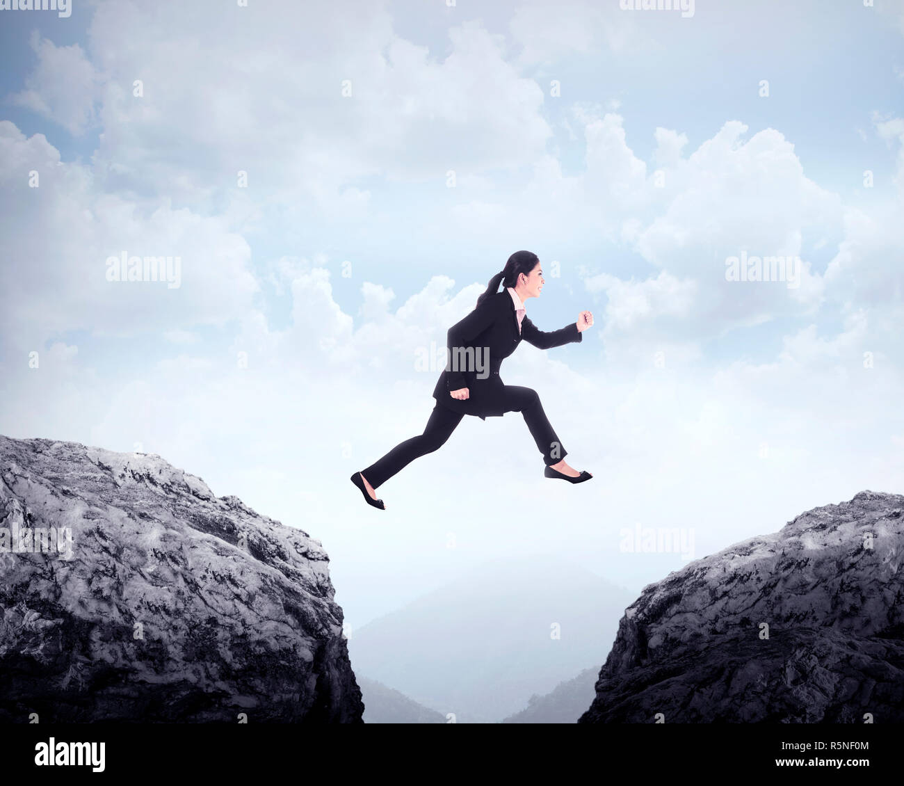 Business woman jumping across hill Stock Photo - Alamy