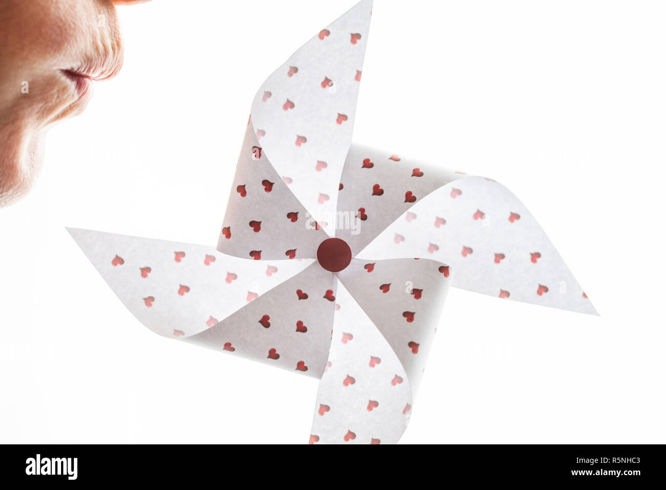 Woman blowing a hearts paper pinwheel isolated on white background ...