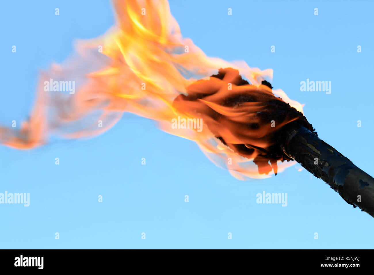 Closeup of flaming torch on blue background with copy space Stock Photo ...