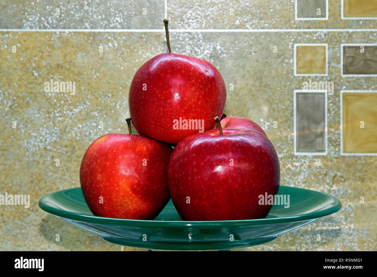 Pyramidal pile of shiny, white-spotted red apples on a green plate ...