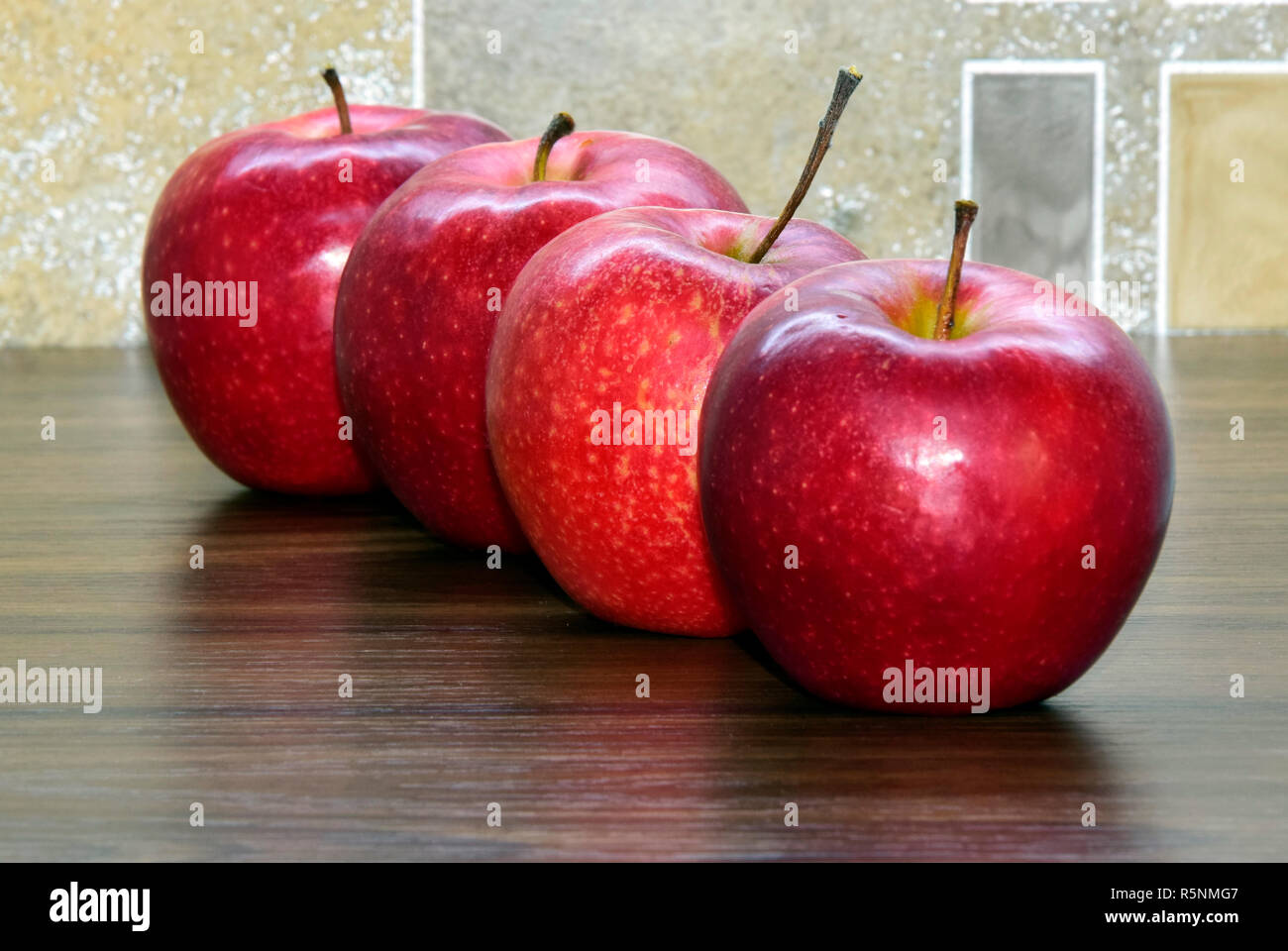 White-spotted shiny red apples placed in queue on a brown wooden ...
