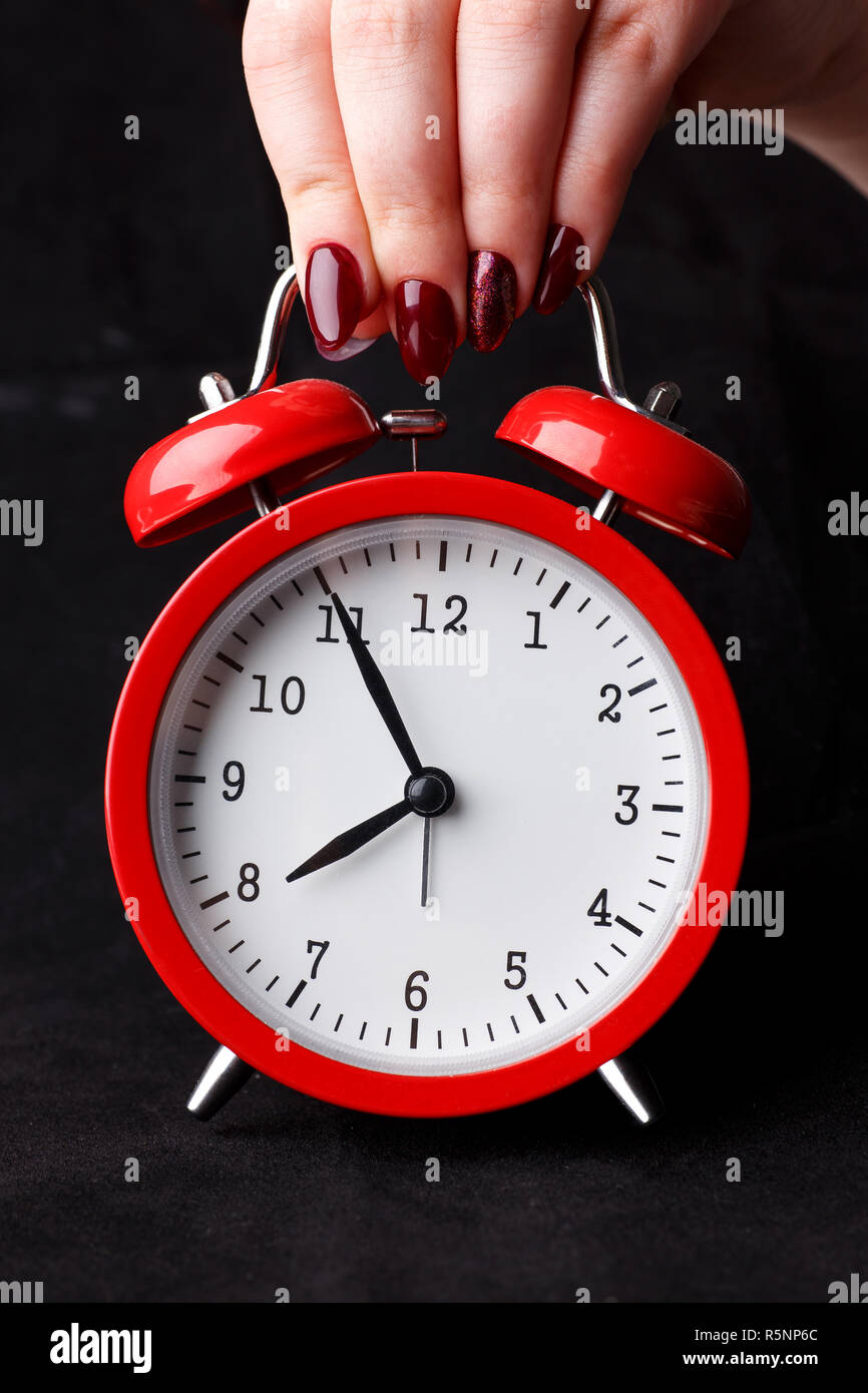 Female arm hold up red alarm clock Stock Photo - Alamy