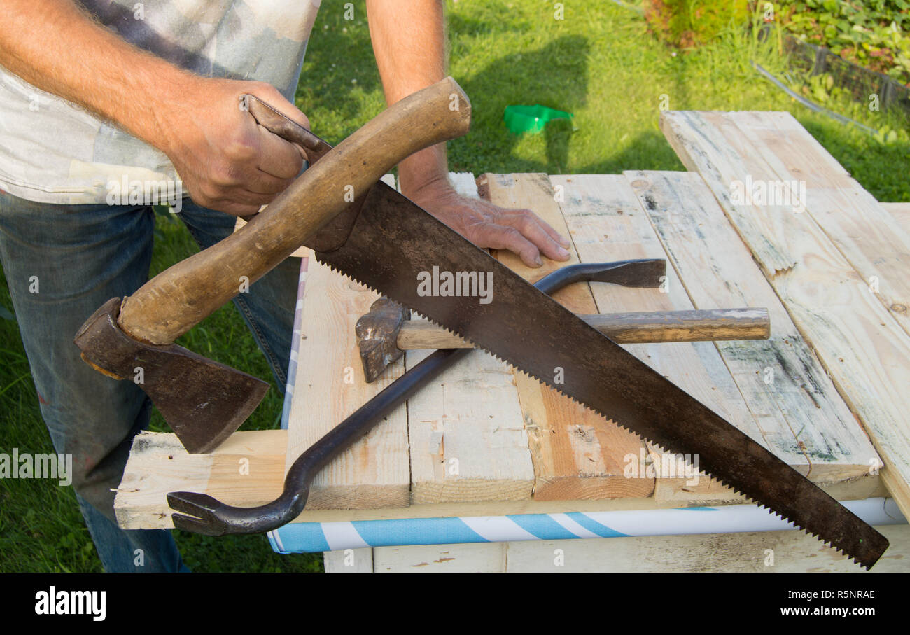 man uses a hacksaw, a hatchet, a claw hammer for construction work in ...