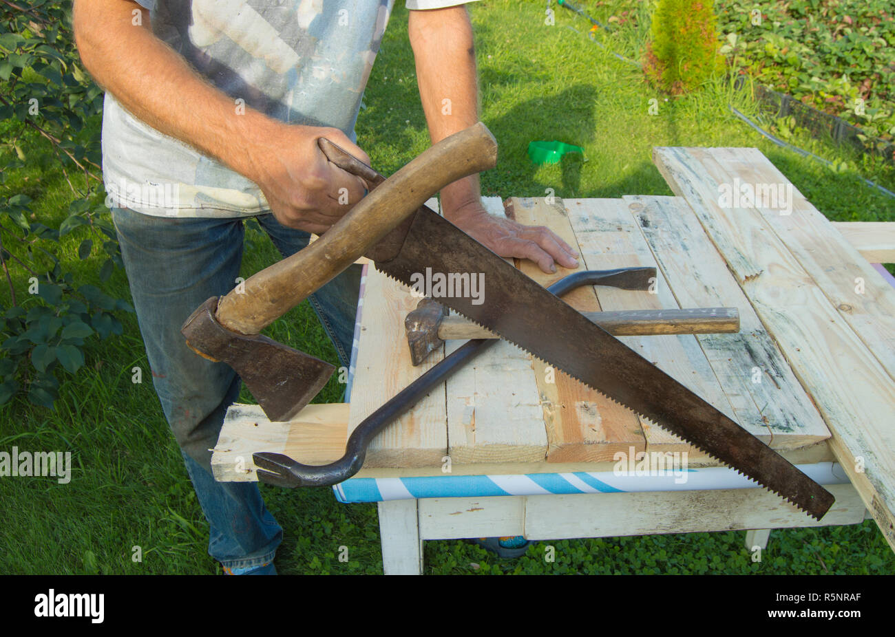 man uses a hacksaw, a hatchet, a claw hammer for construction work in ...