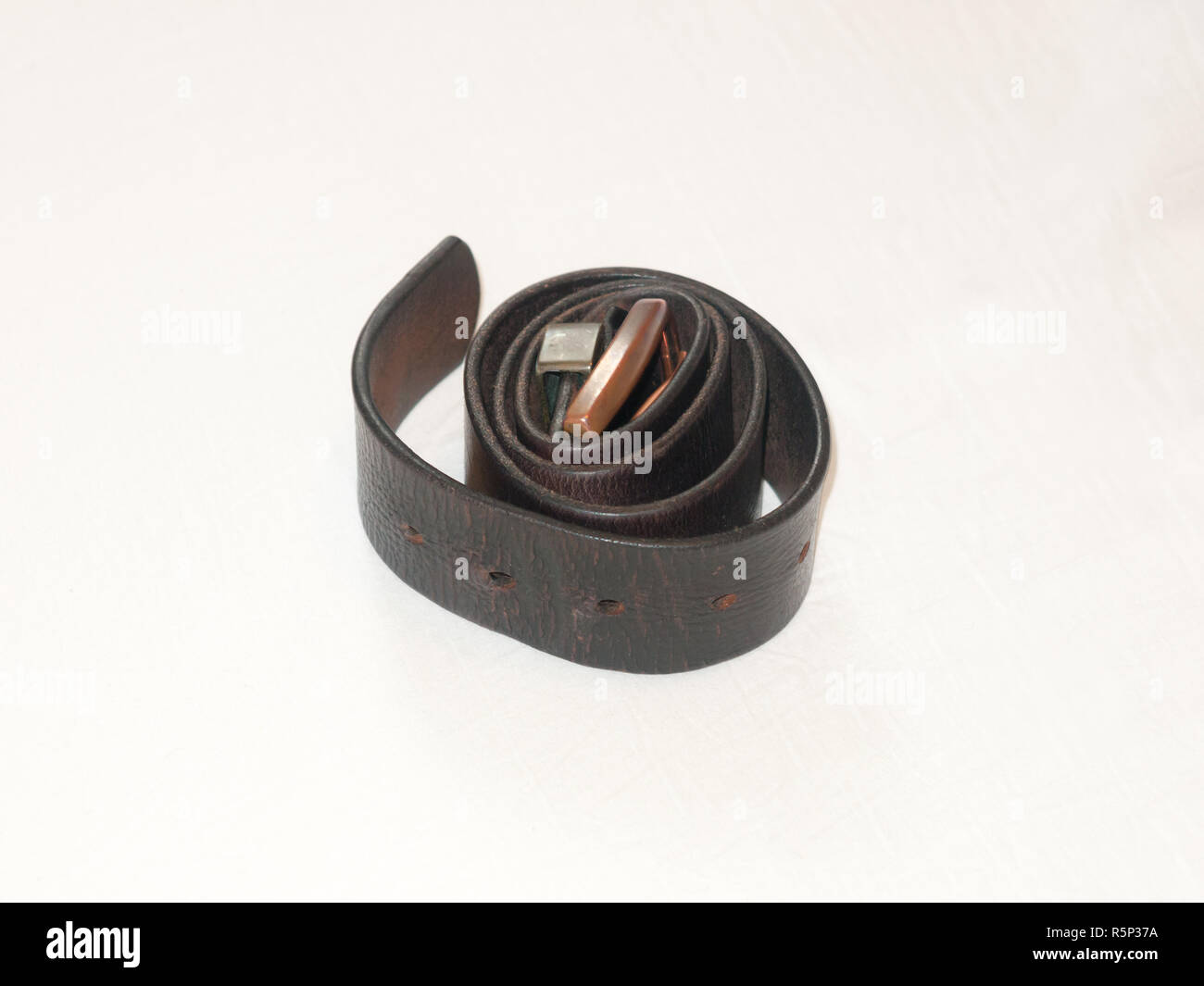 a coiled up black metal belt on the bed Stock Photo - Alamy