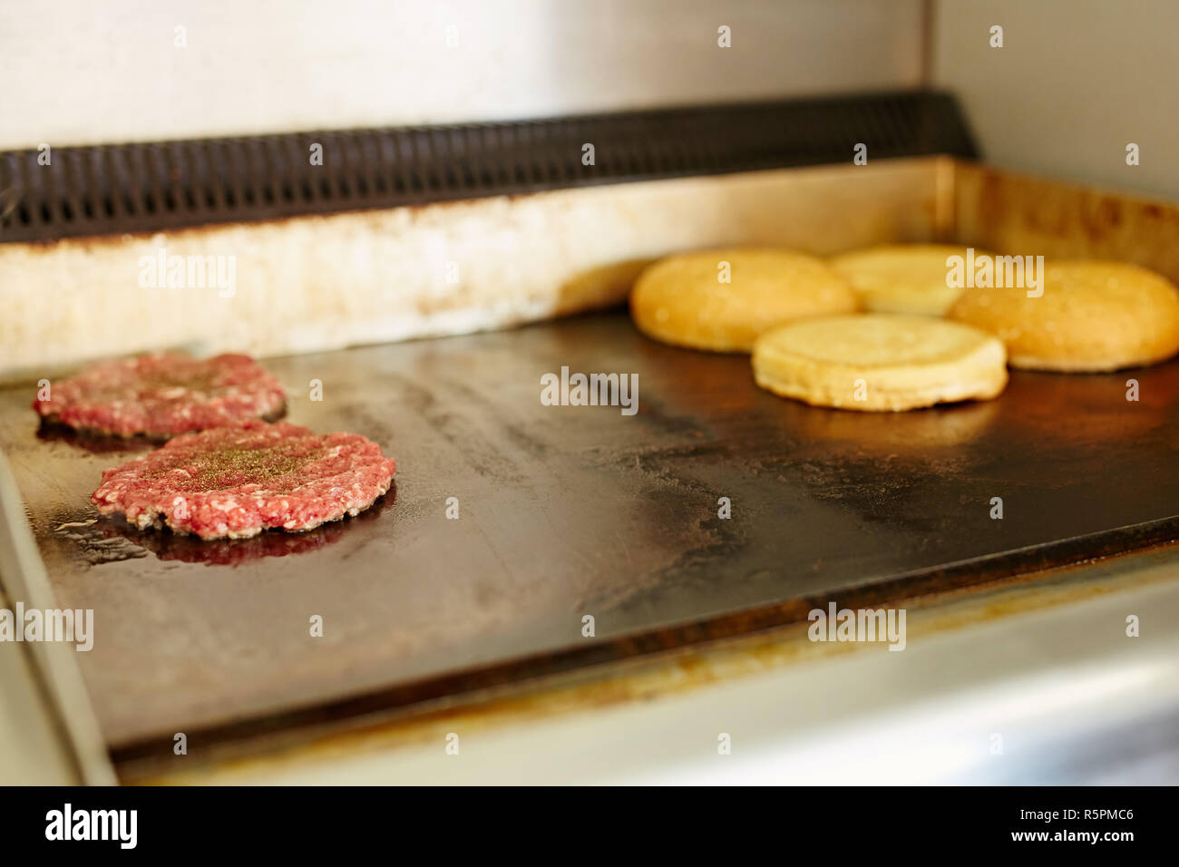 Burger patties frying on a grill with open buns toasting Stock Photo ...