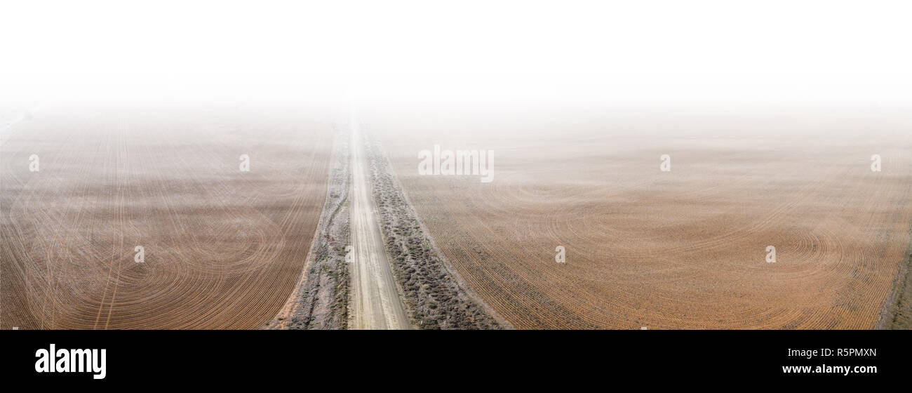 Road vanishing into white mist between plowed fields in Australian ...