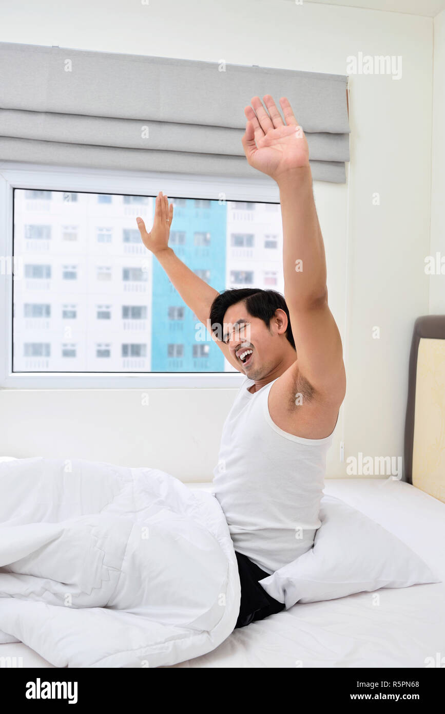 Young asian man waking up and stretching his arms Stock Photo - Alamy