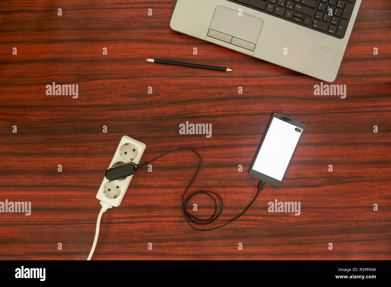 Above view of a smartphone connected to electric socket on a power ...
