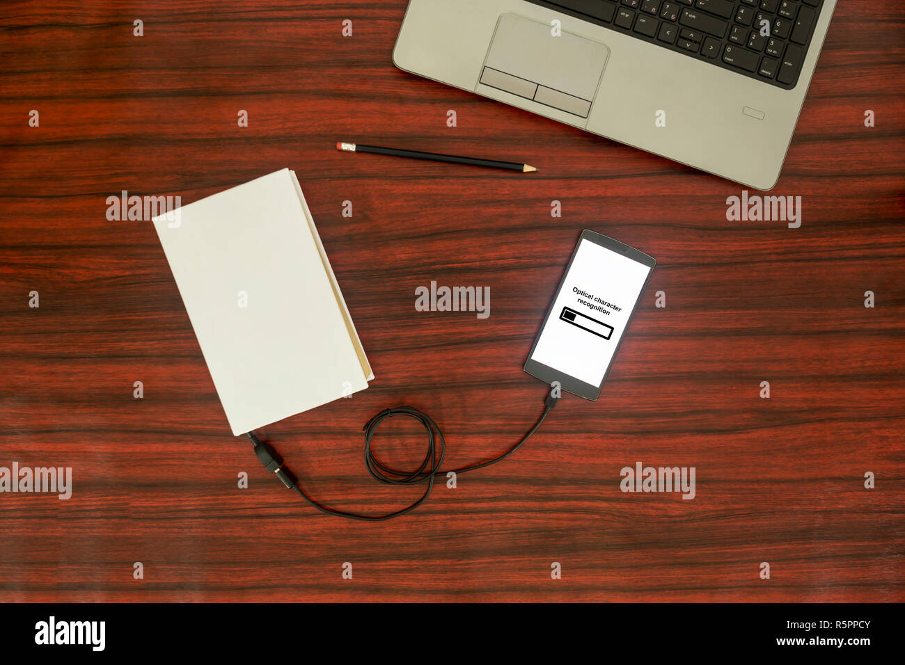 Above view of a book connected to a smartphone through an USB cable on ...