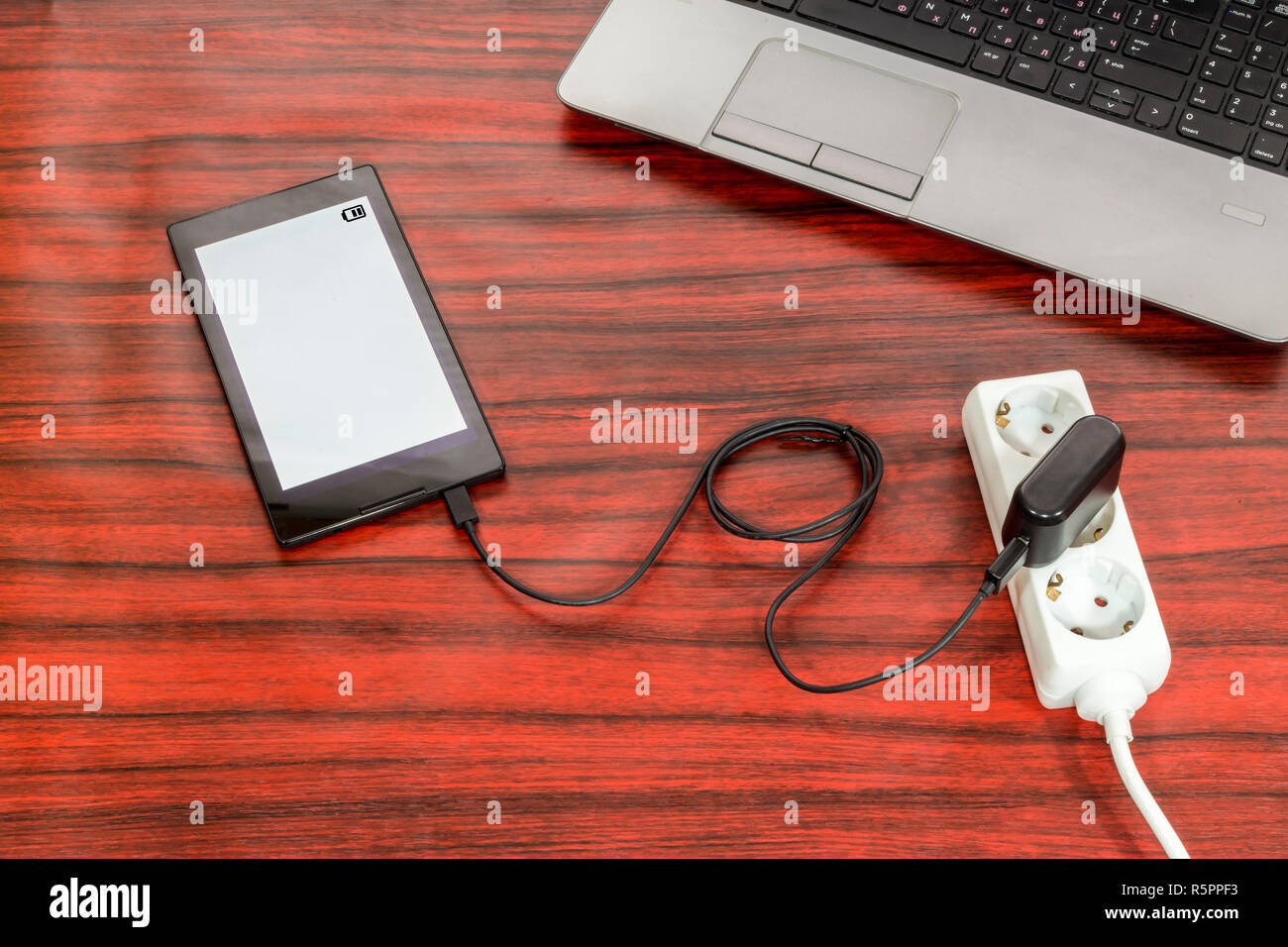Tablet charging concept - Tablet connected to electric socket on a ...