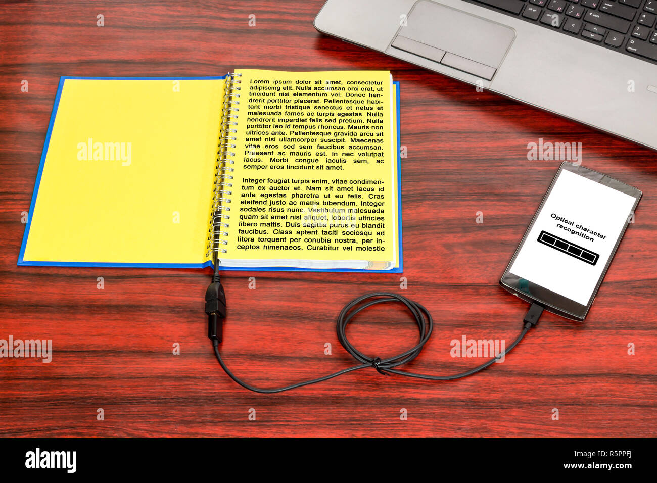 Notepad connected to a smartphone through an USB cable on a desk ...