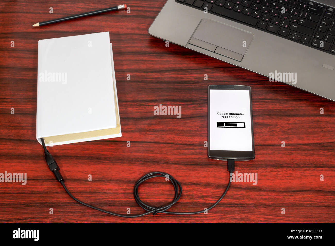 Book connected to a smartphone through an USB cable on a desk. Optical ...