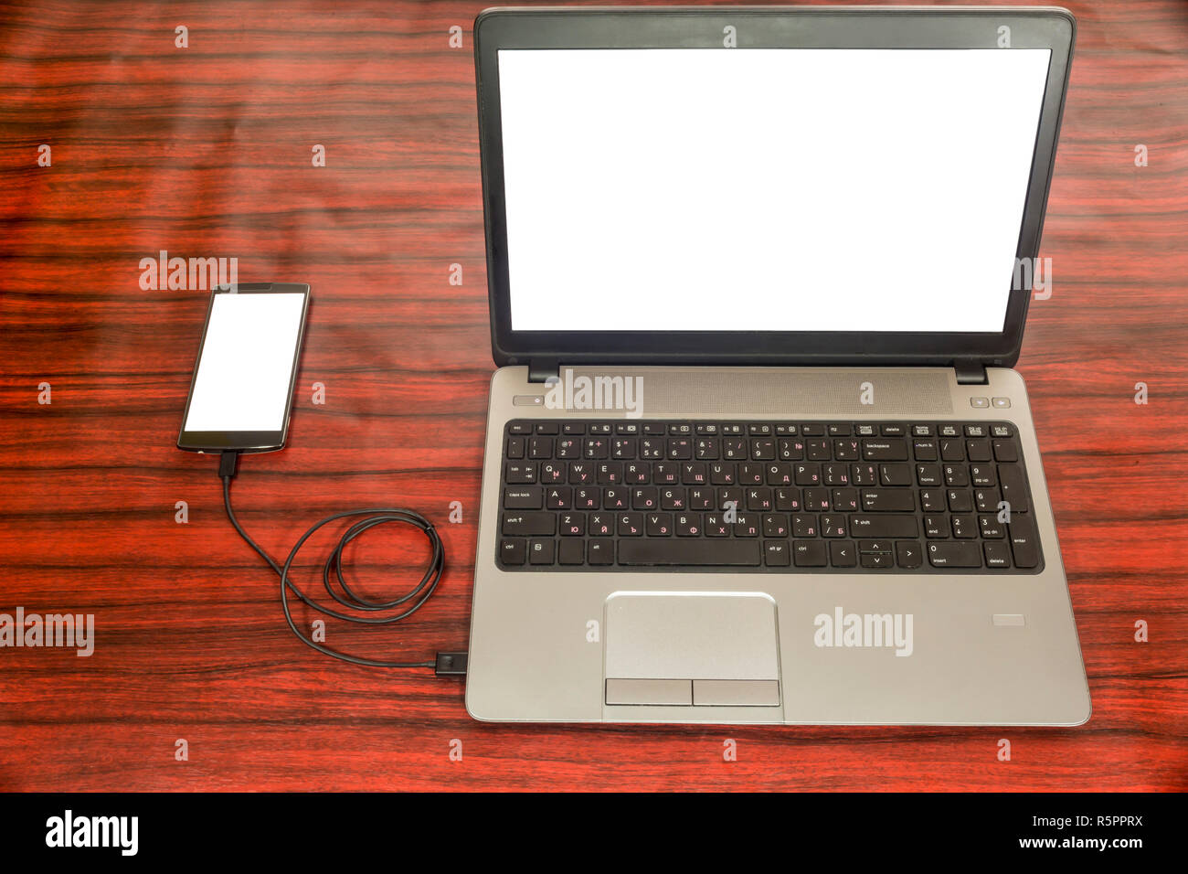 Data transfer concept. Cellphone and a laptop connected with USB cable ...