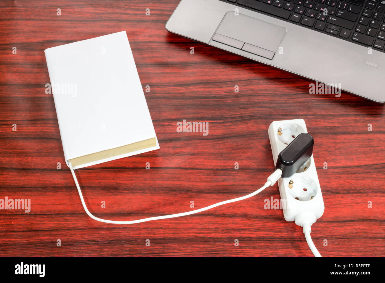 Book charging concept - Book connected to electric socket on a power ...