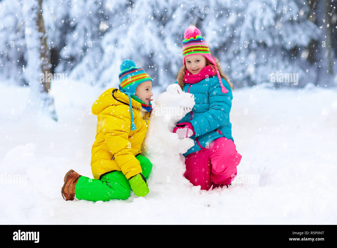 Kids making snowman in snowy winter park. Children play in snow. Boy ...