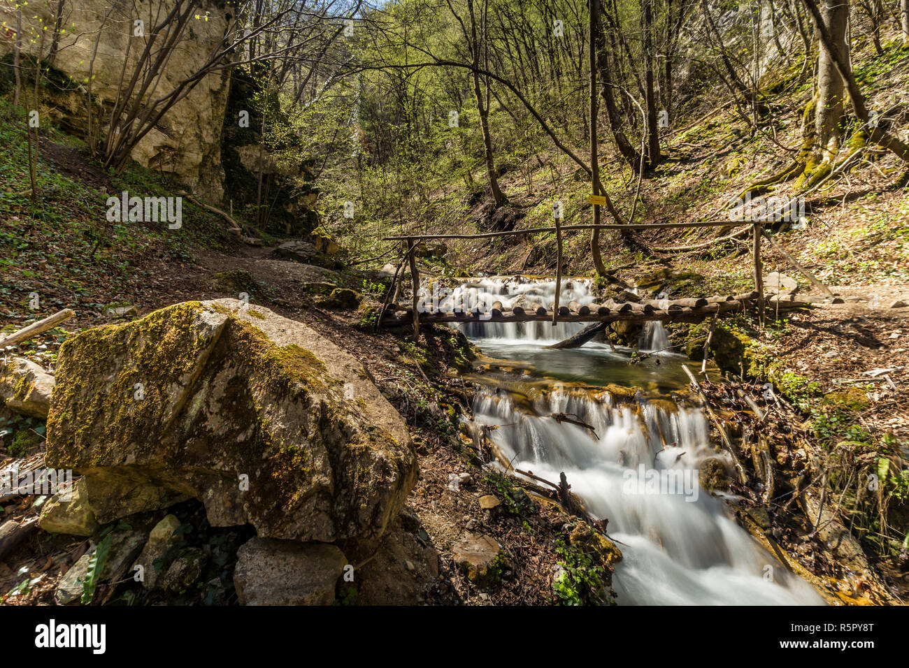 Beautiful small waterfall with a wooden bridge for crosing the river ...
