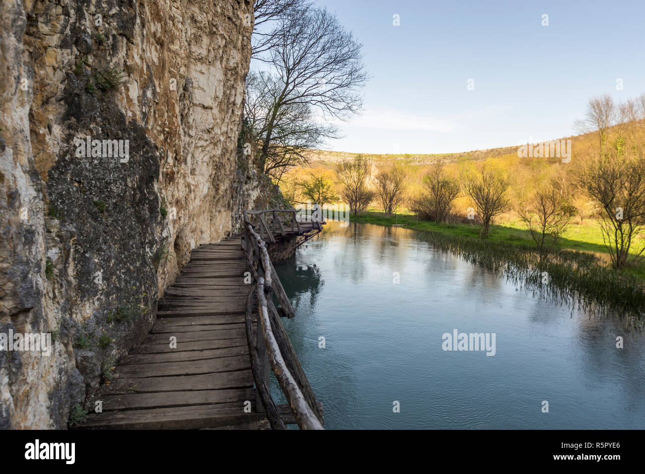 Wooden walkway hanging alongside a vertical cliff crossing a river on ...