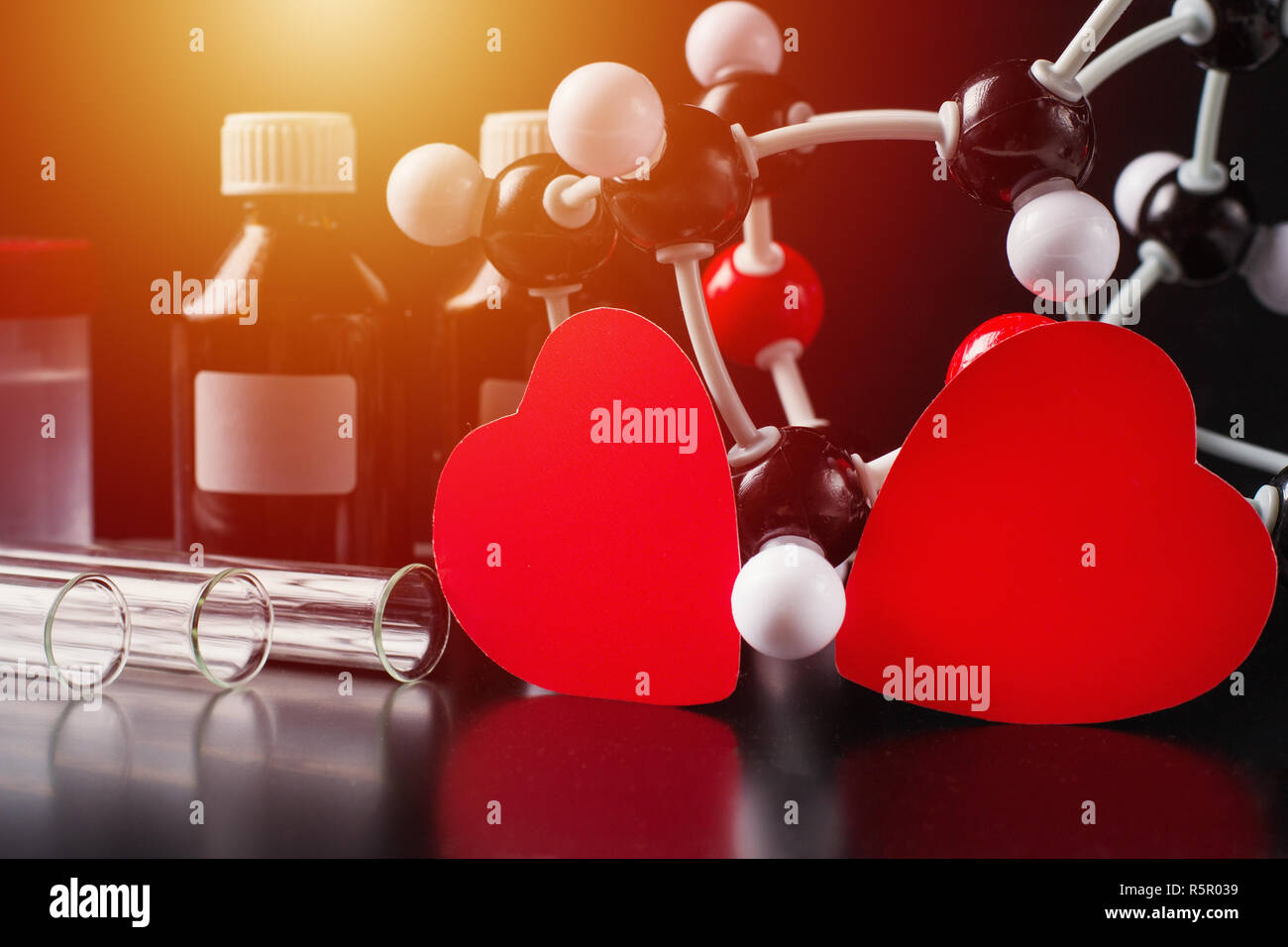 Two red paper hearts and molecular structure model on black background ...