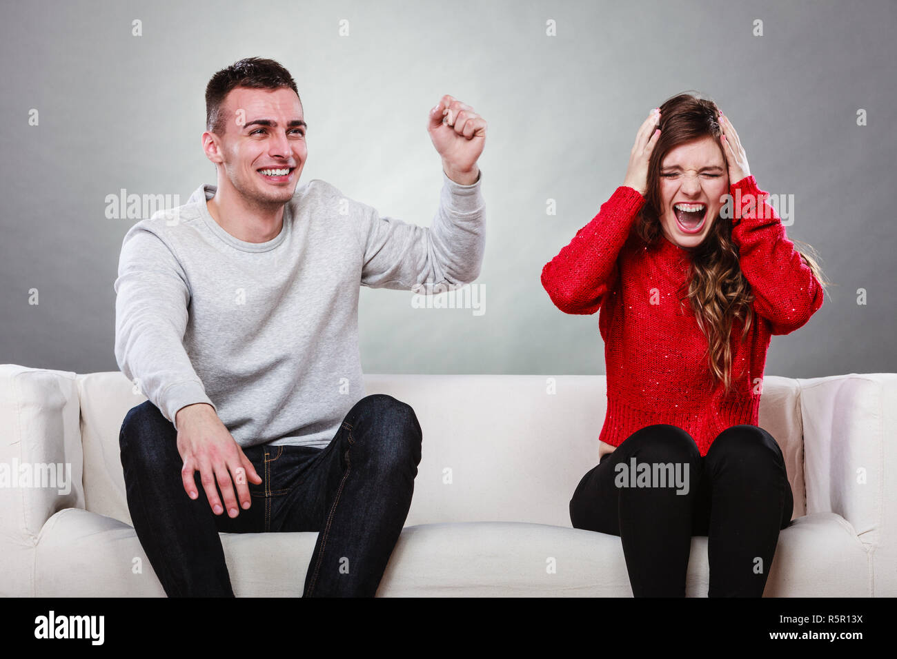 Furious angry upset woman and happy joyful husband sitting on sofa at ...