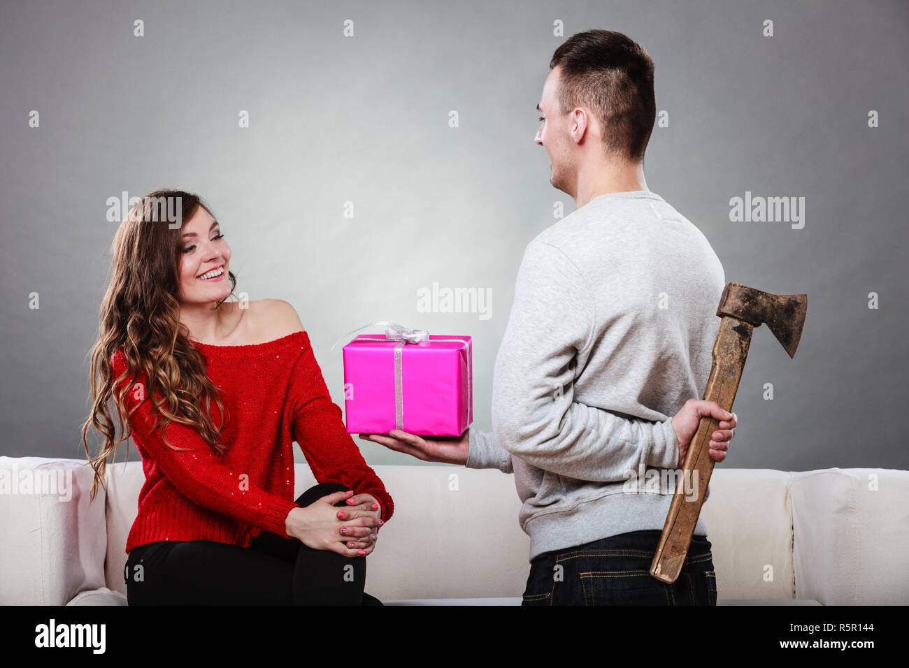 Sneaky insincere man holding axe giving gift present box to woman ...