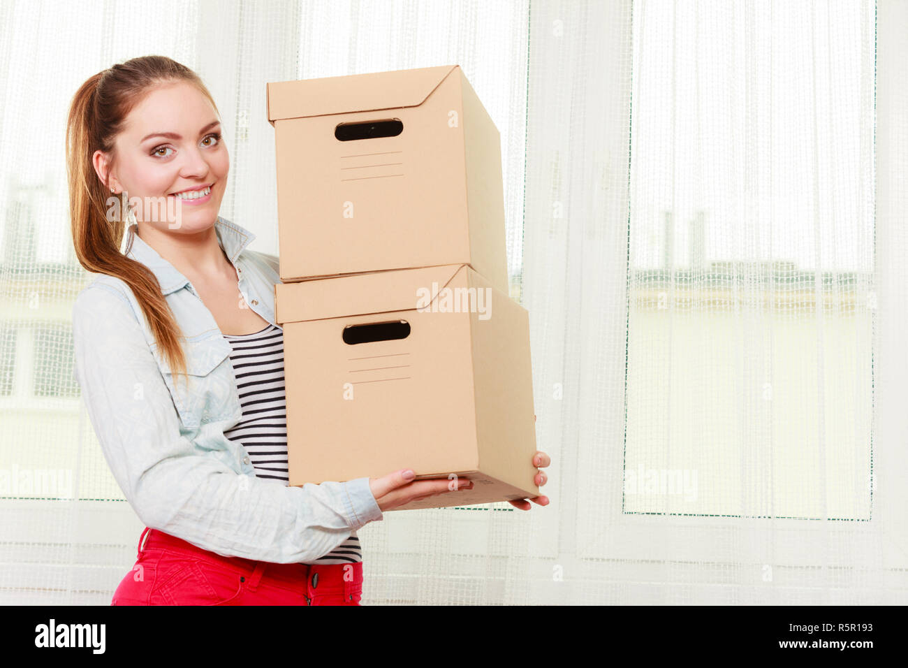 Woman moving in carrying cartons boxes. Young girl unpacking at new ...