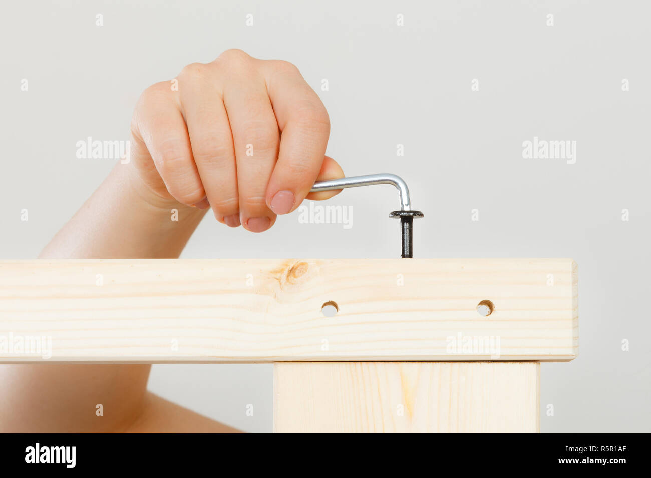 Human hand assembling wooden furniture using hex key. DIY enthusiast ...