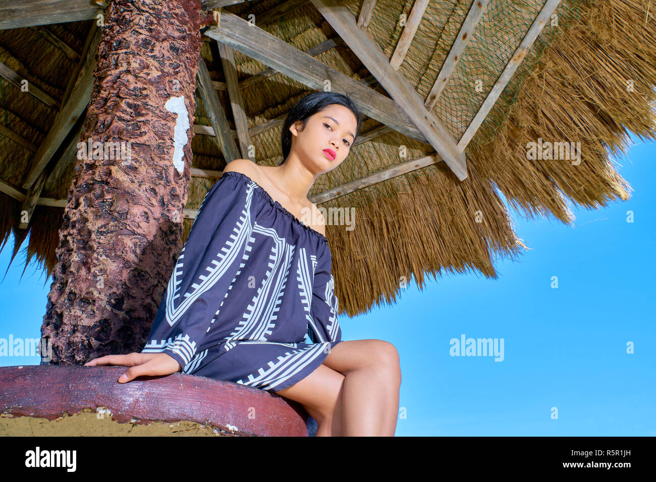 Beautiful woman posing - looking down the camera, sitting on table ...