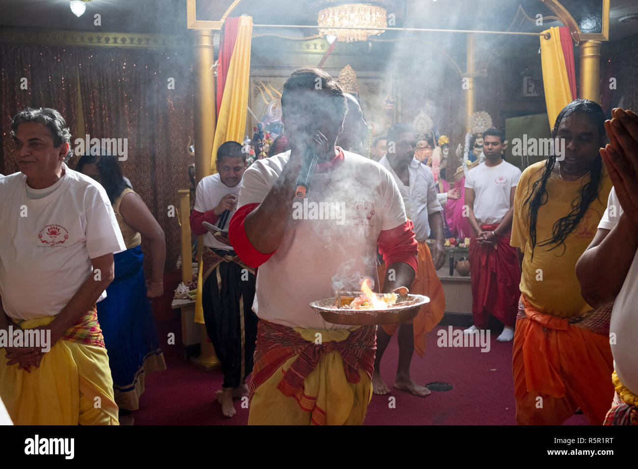 A scene from a service at a Hindu temple where a man is chanting into a ...