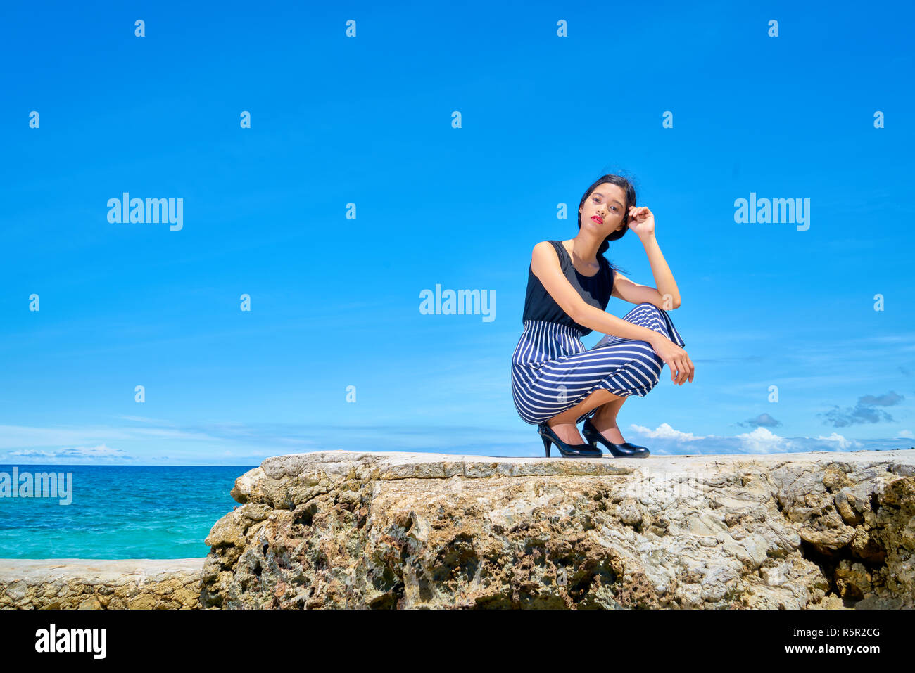 Beautiful woman posing - sitting on the edge, hands on head Stock Photo ...