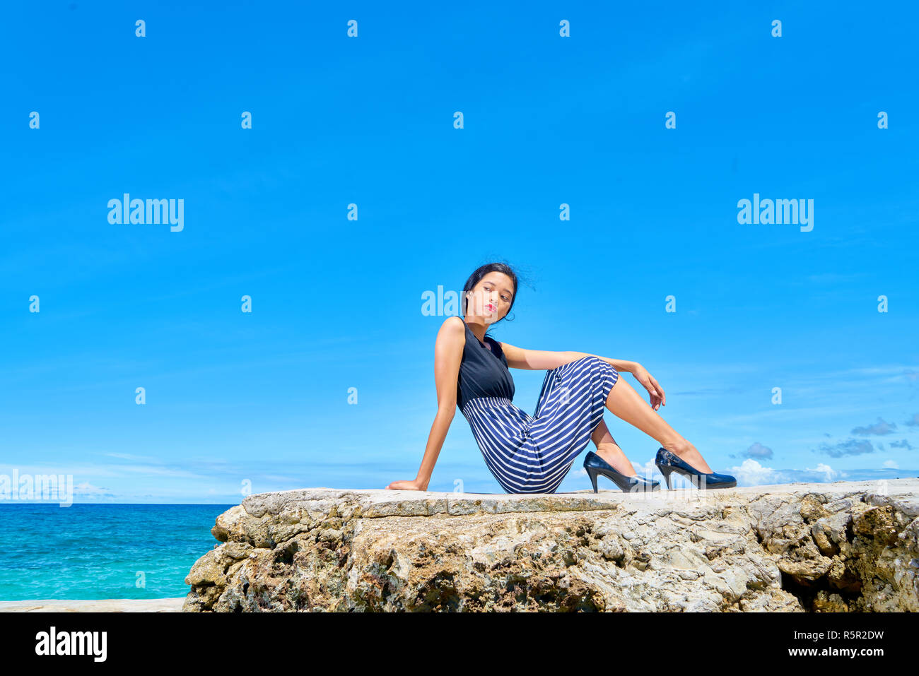 Beautiful woman posing - sitting on edge and looking away Stock Photo ...