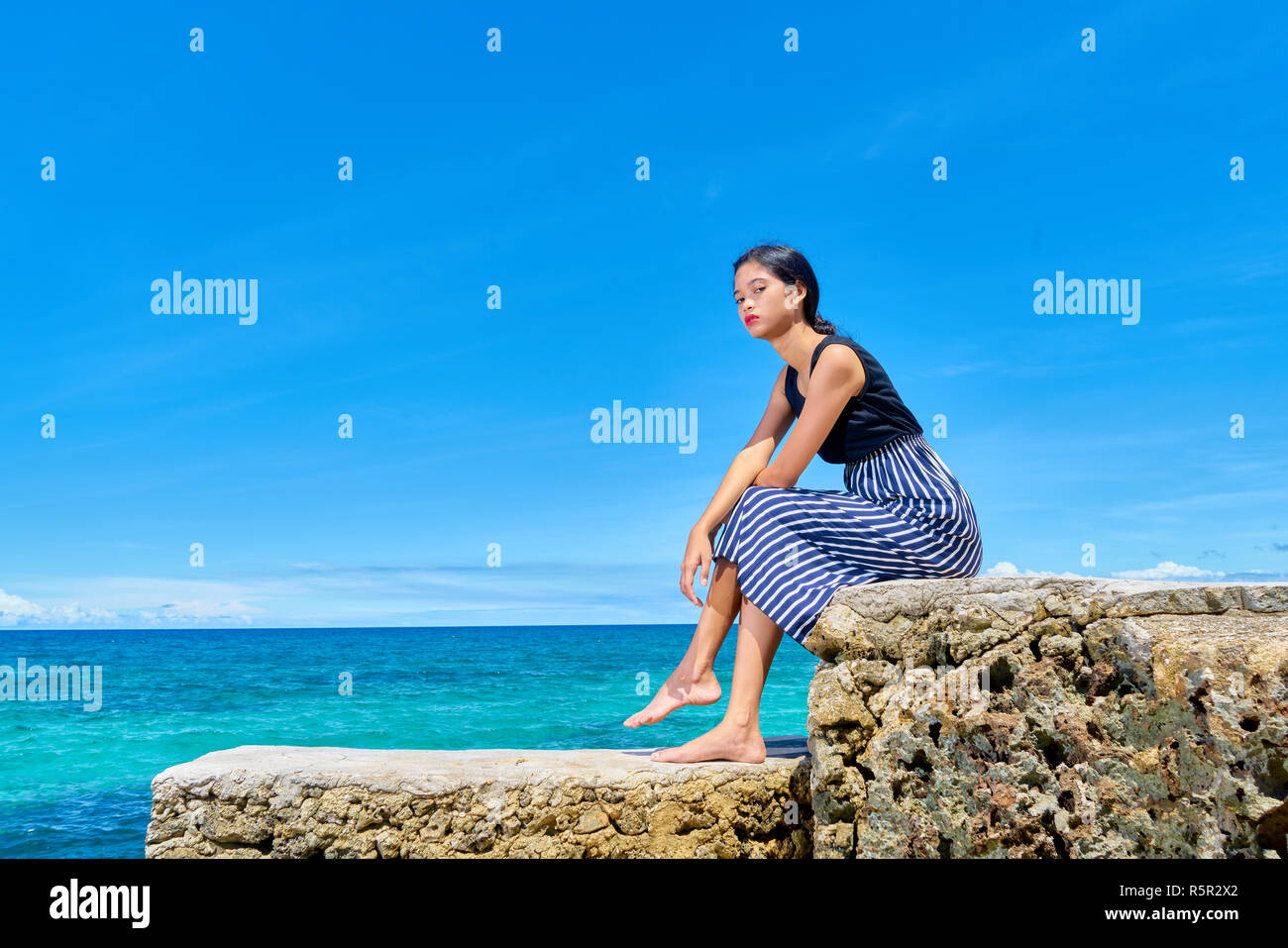 Beautiful woman posing - sitting on edge, thinking and looking away ...