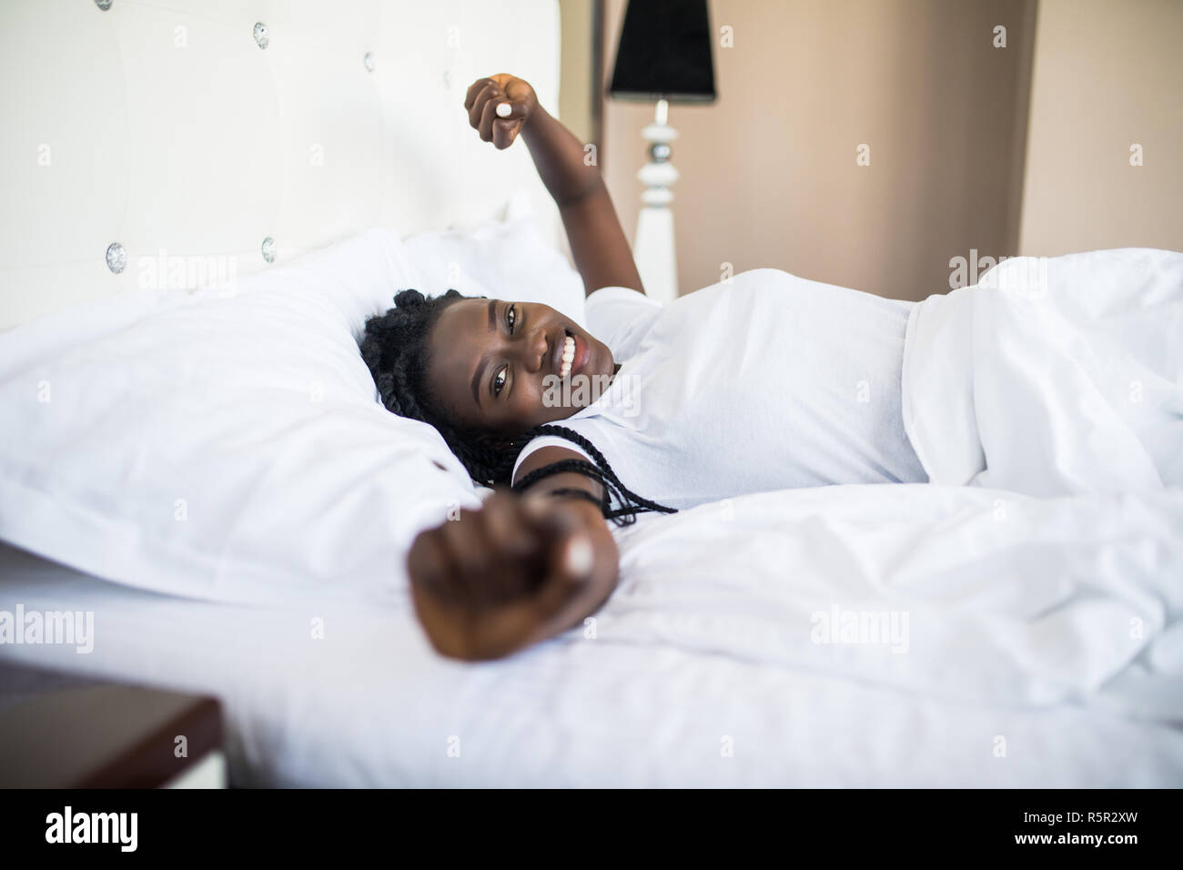 Beautiful woman waking up in her bed, she is smiling and stretching ...