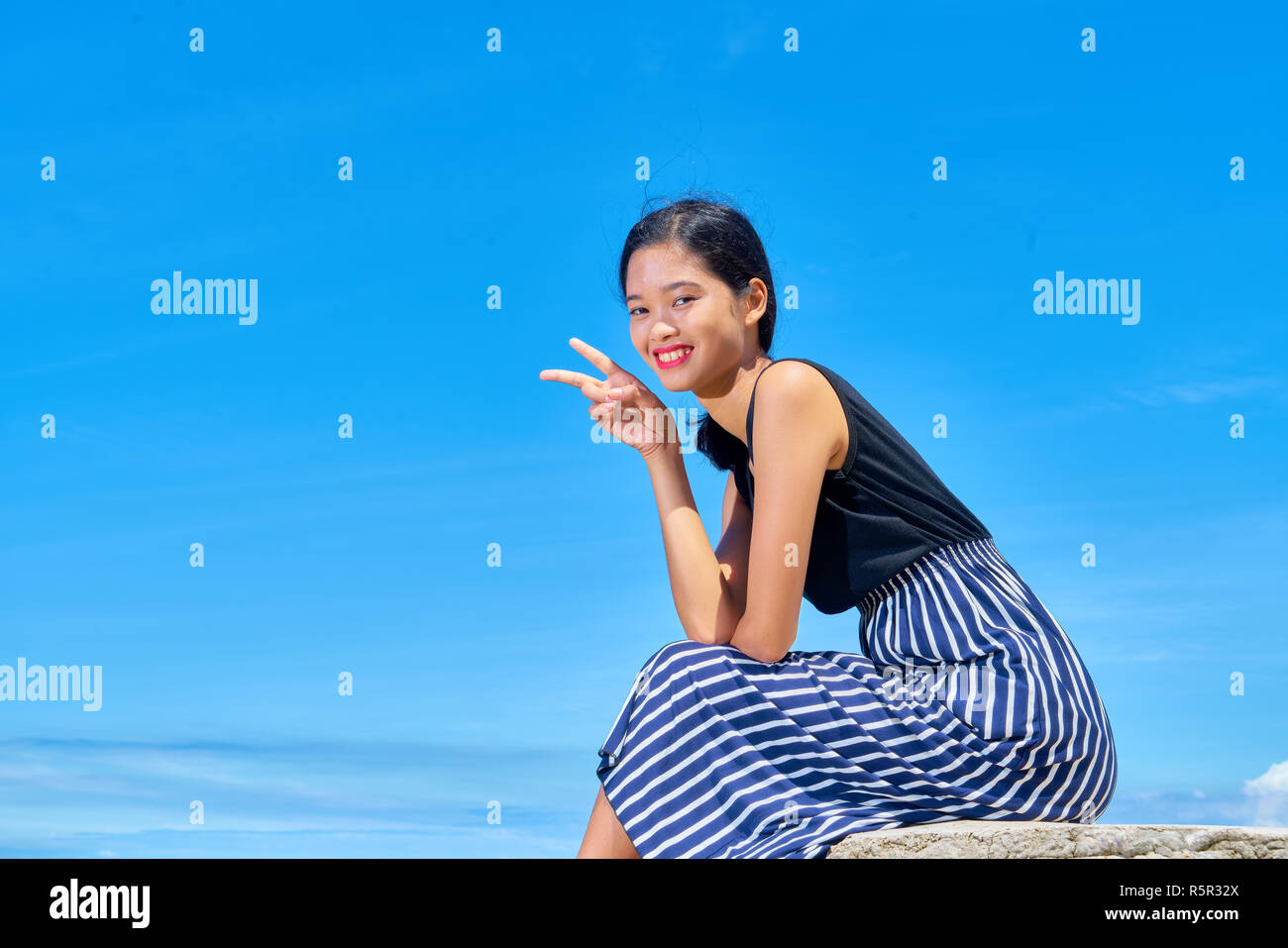 Beautiful woman posing -sitting, smiling face, hands sign, peace sign ...