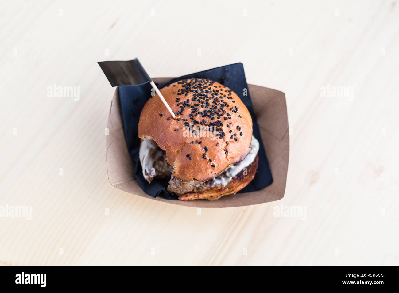 Hamburger on wooden table, one bite taken out of it Stock Photo - Alamy