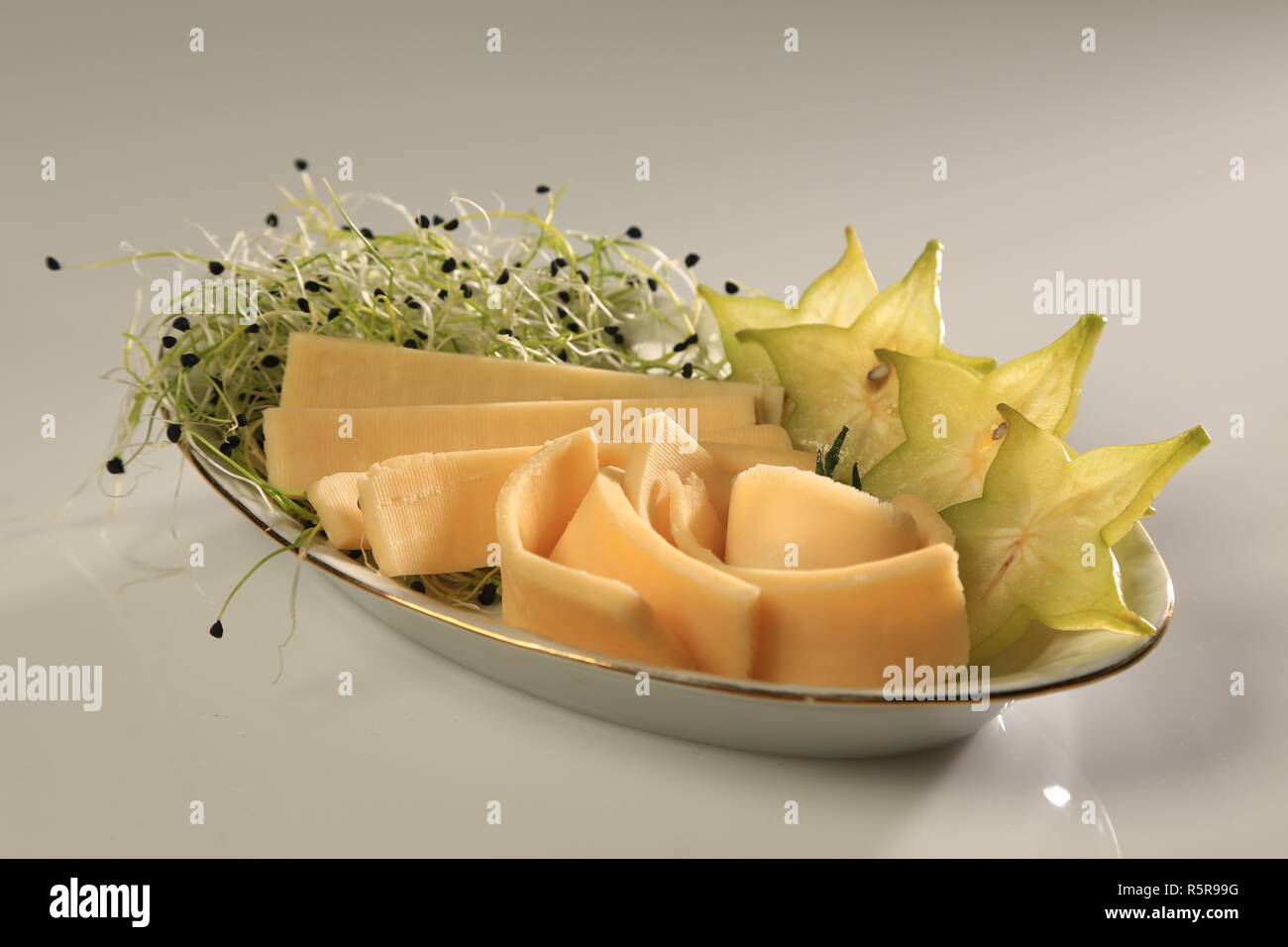 Slices of chhese with slices of starfruit and sprouts on the side Stock ...
