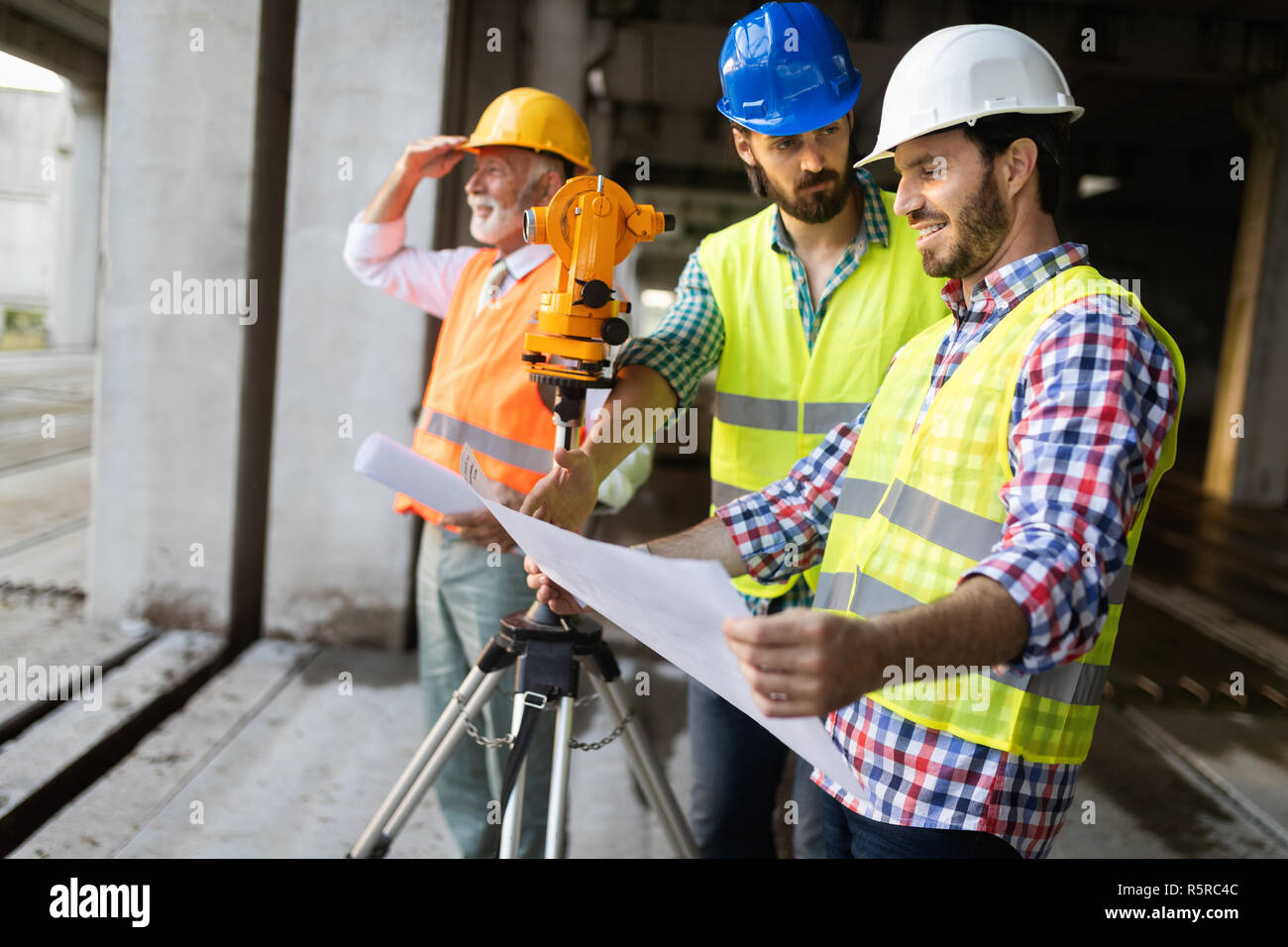 Engineer, foreman and worker discussing in building construction site ...