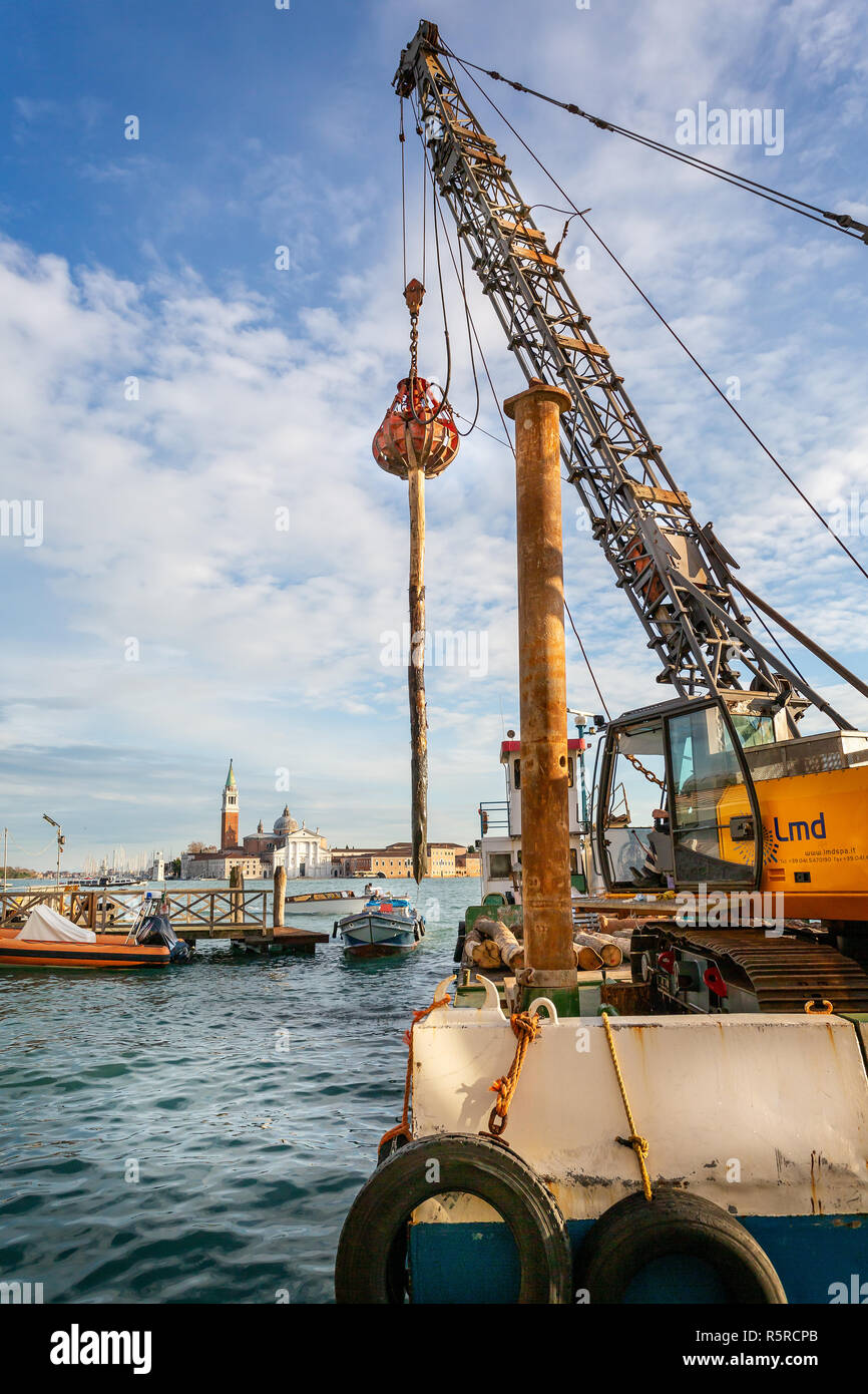 Floating crane installing wooden piling to maintain the canals in ...