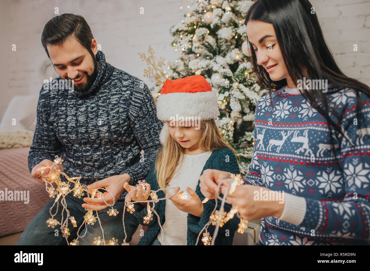 Beautiful young family enjoying their holiday time together, decorating ...