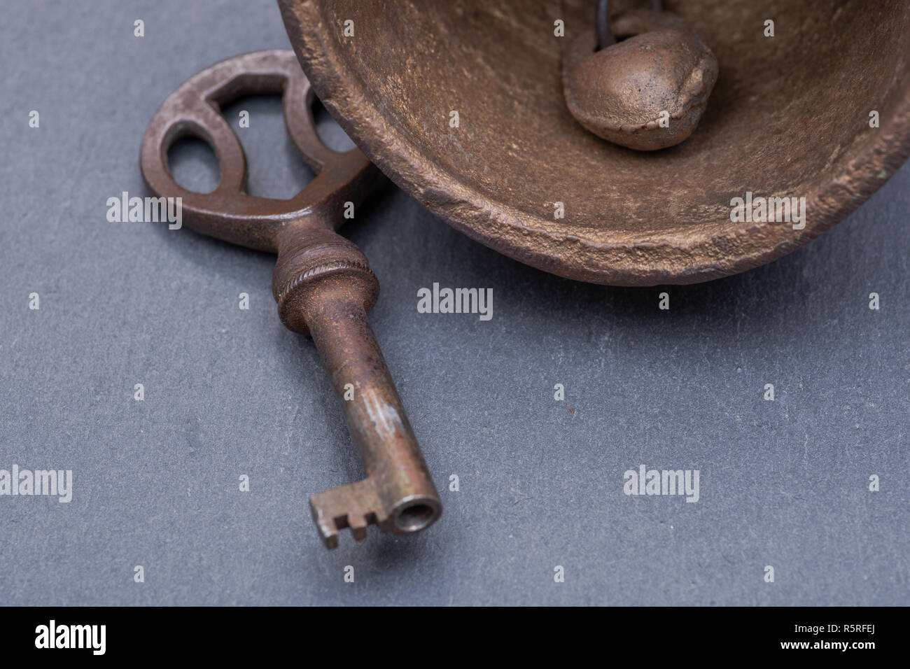 Old antique vintage metallic key and bell on natural stone background ...