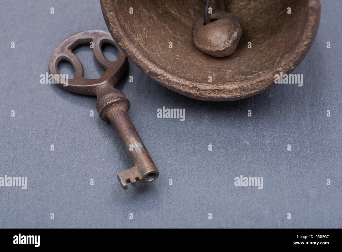 Old antique vintage metallic key and bell on natural stone background ...