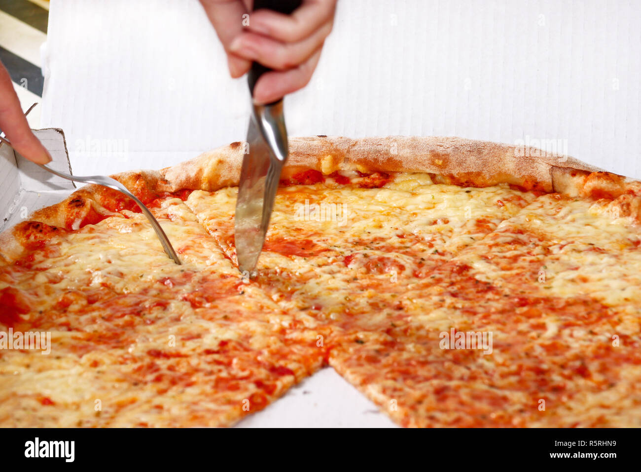 Woman's hand with a knife cut the pizza. Delicious pizza Margarita ...
