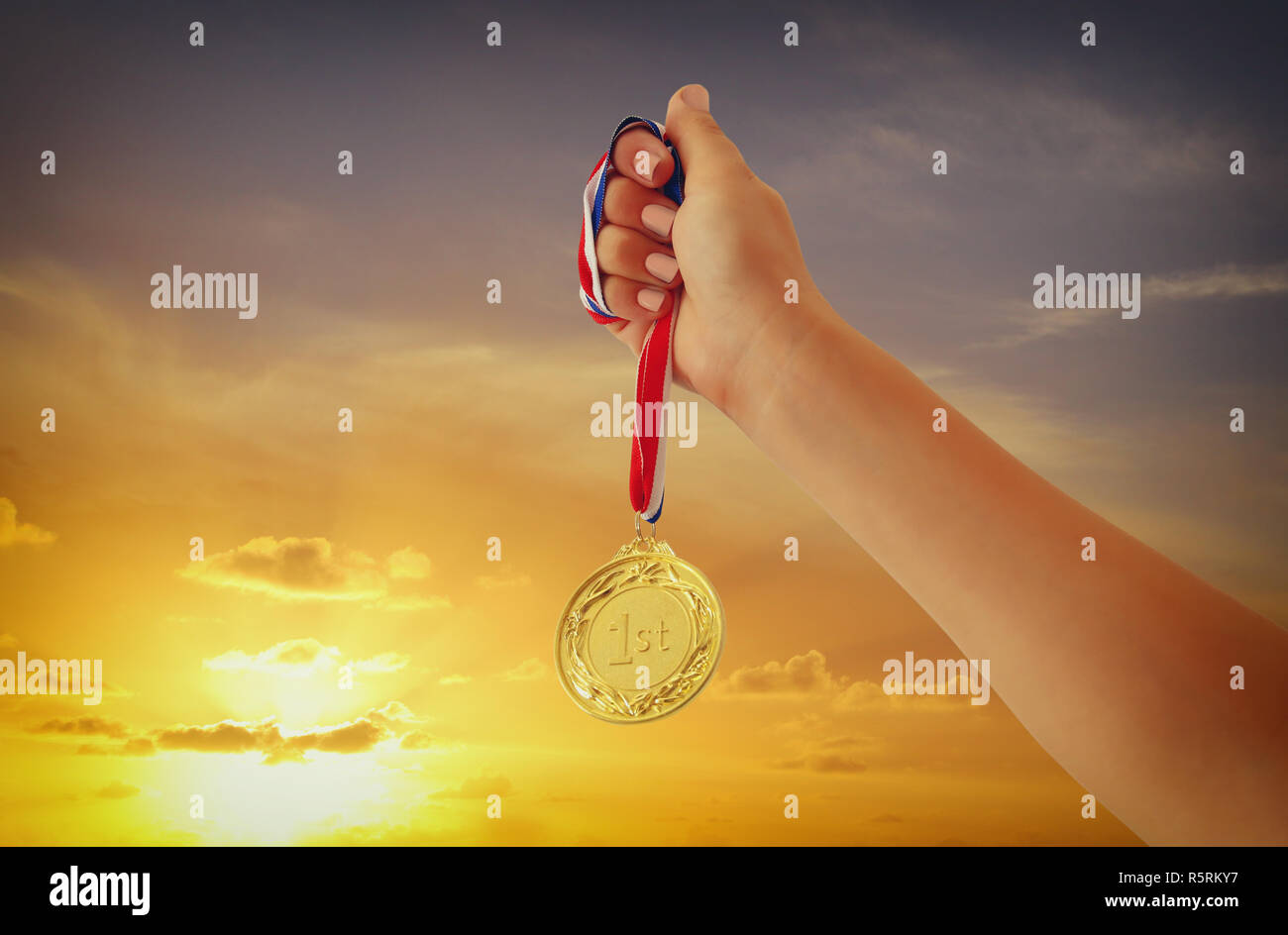 woman hand raised, holding gold medal against sky. award and victory ...