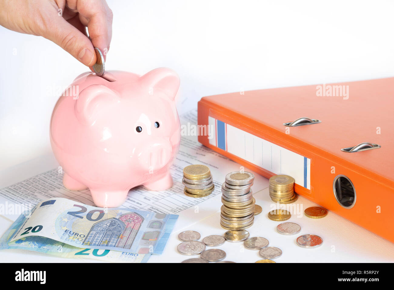 Hand inserting coin into piggybank Stock Photo - Alamy