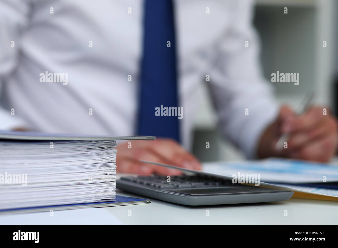 White binder lie at worktable with male clerk worker in background ...