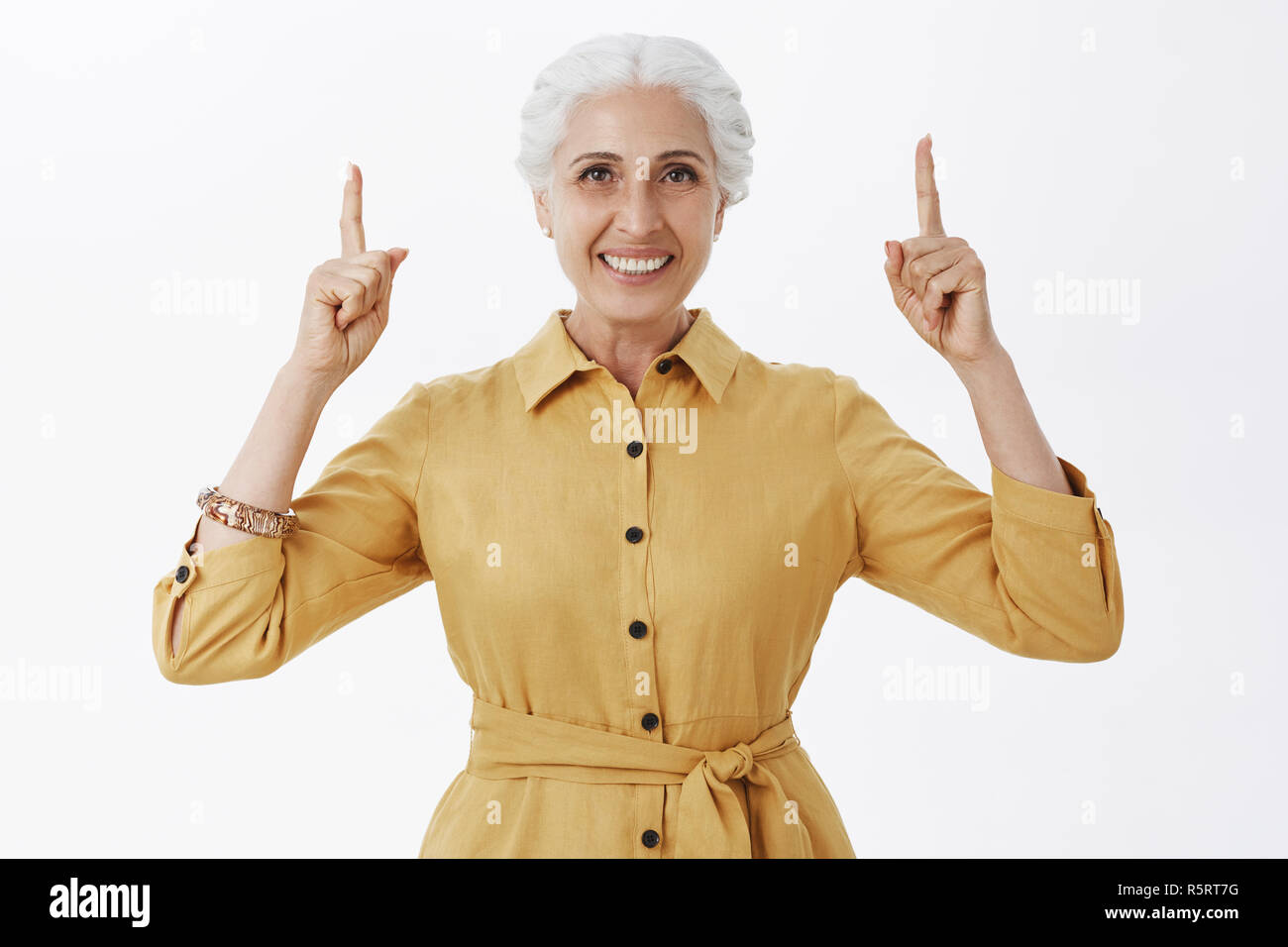 Energized active and happy old woman with white hair in stylish yellow ...