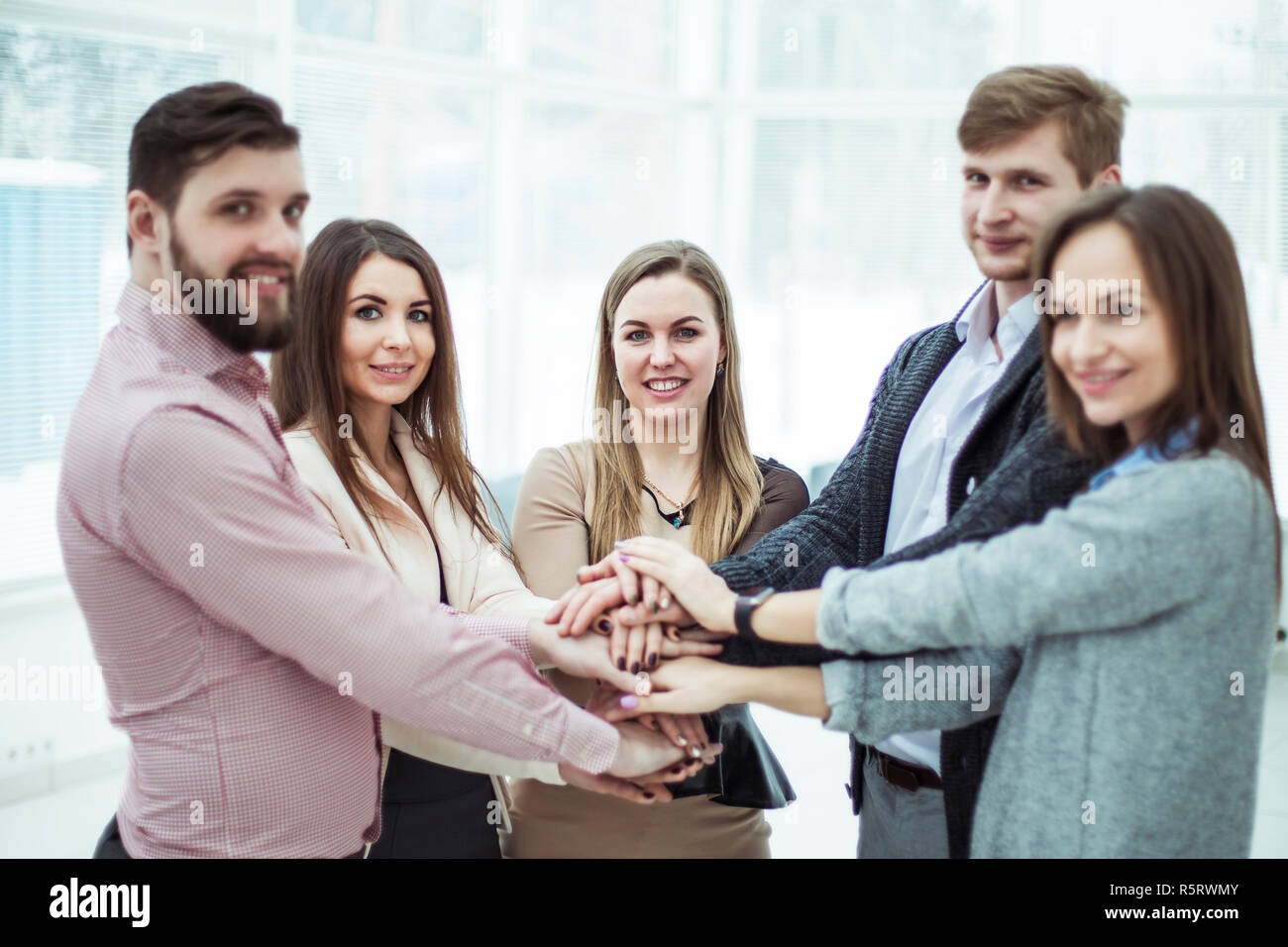 concept of teamwork:friendly business team standing in a circle, hands ...