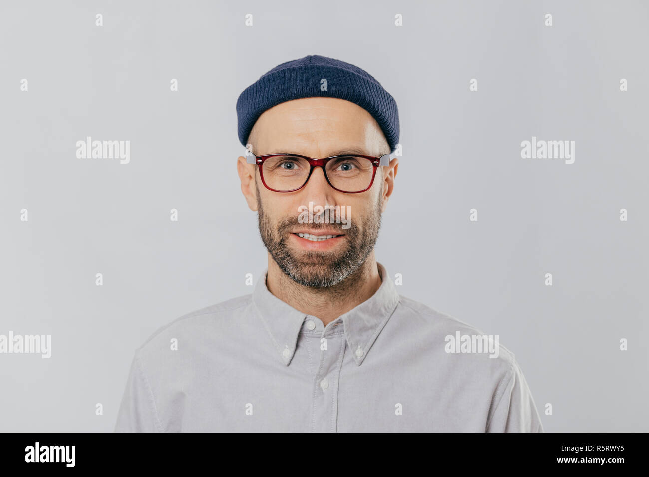Headshot of handsome unshaven man wears transparent glasses, headgear ...