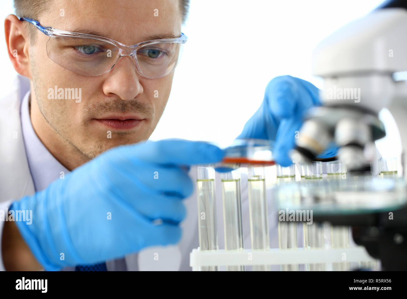A male chemist holds test tube of glass in his hand Stock Photo - Alamy